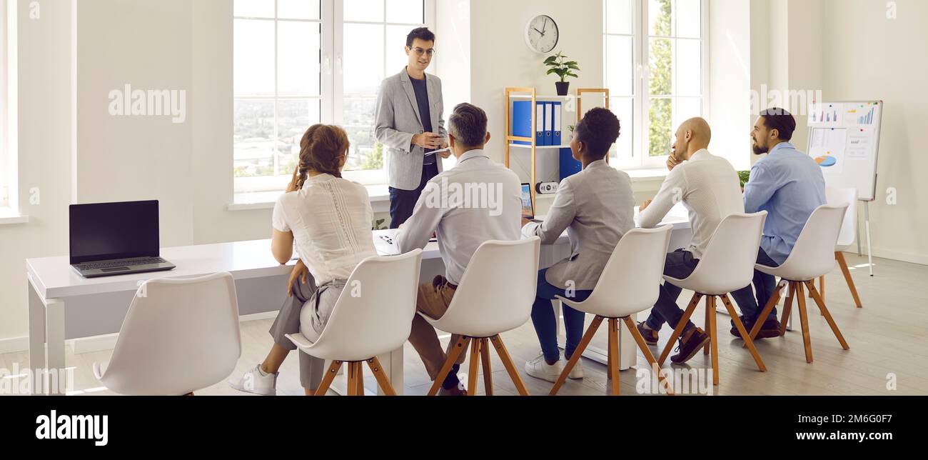 Man speaking in front of his colleagues discusses business matters with ...