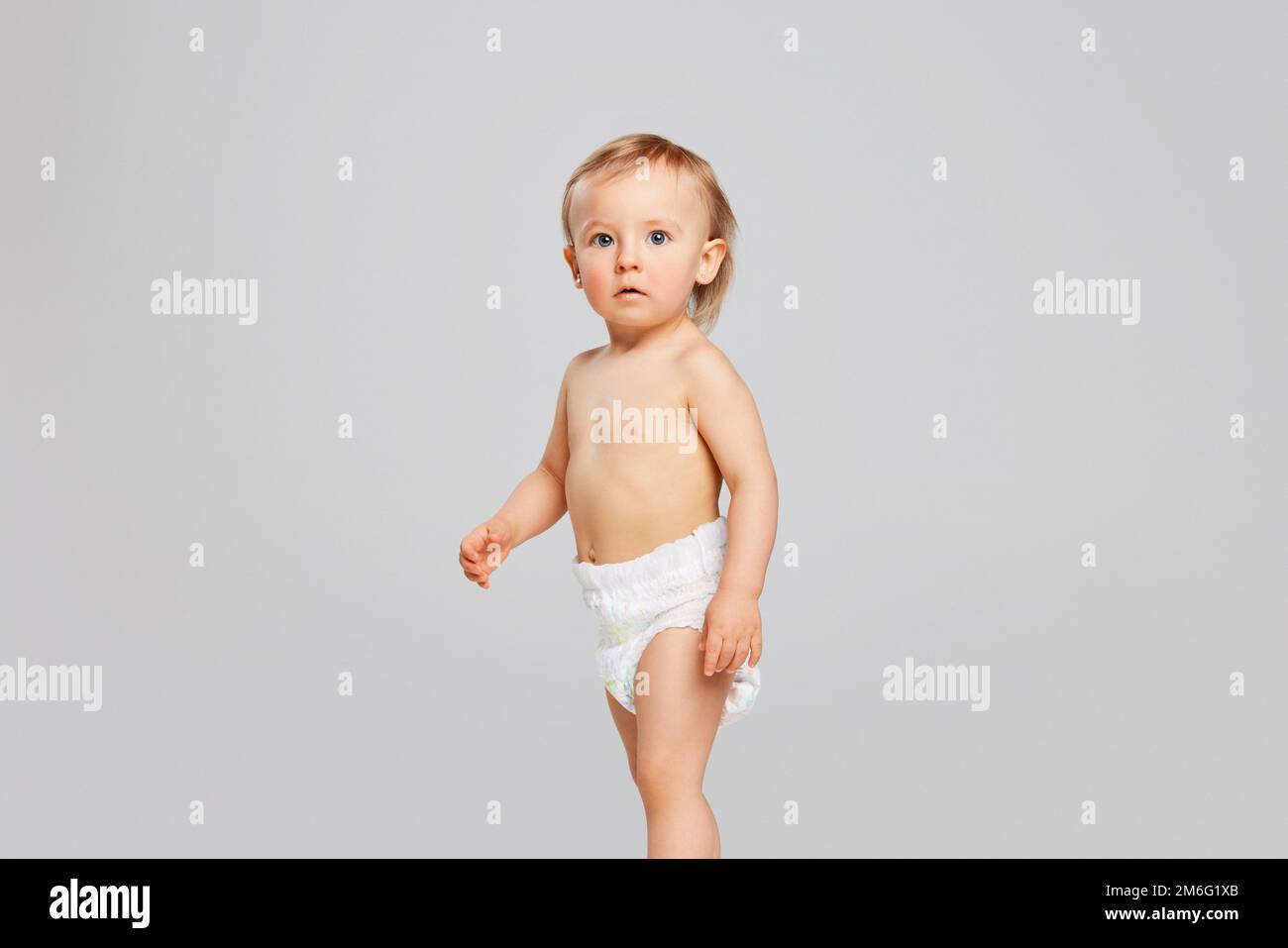 Little sad scared toddler girl, baby in diaper standing isolated on ...