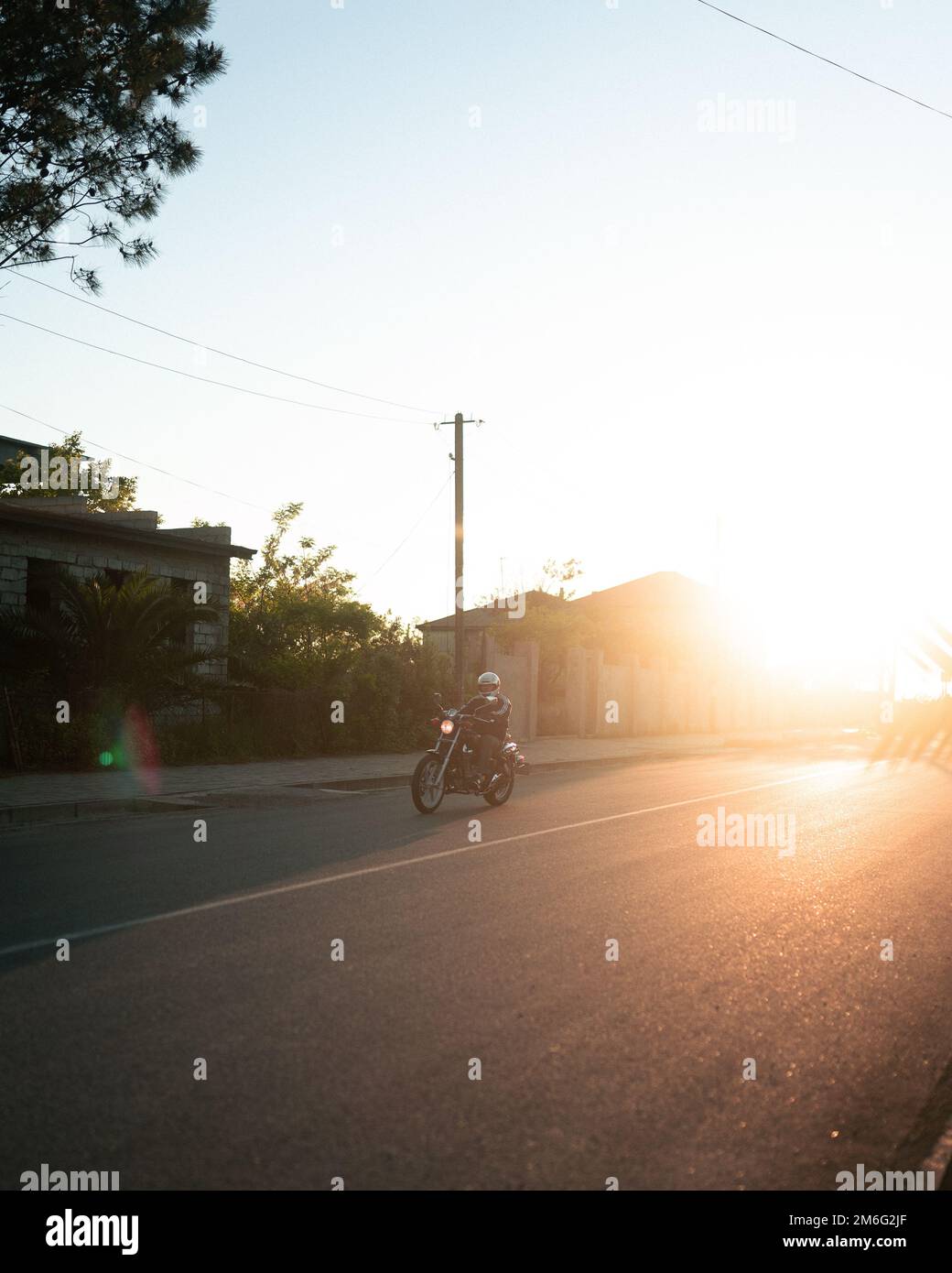 A vertical shot of a man driving a motorcycle at sunset Stock Photo - Alamy