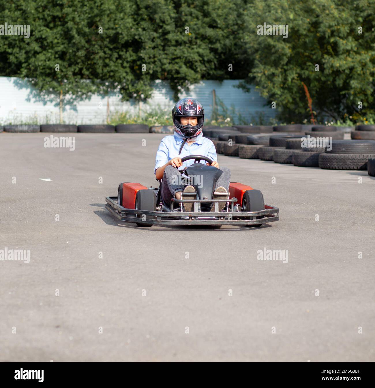 A girl or a woman in a helmet rides a go-kart on a special track Stock ...