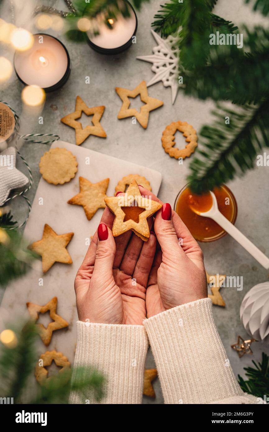 Woomen hands make Linzer Augen cookies biscuits with apricot confiture ...