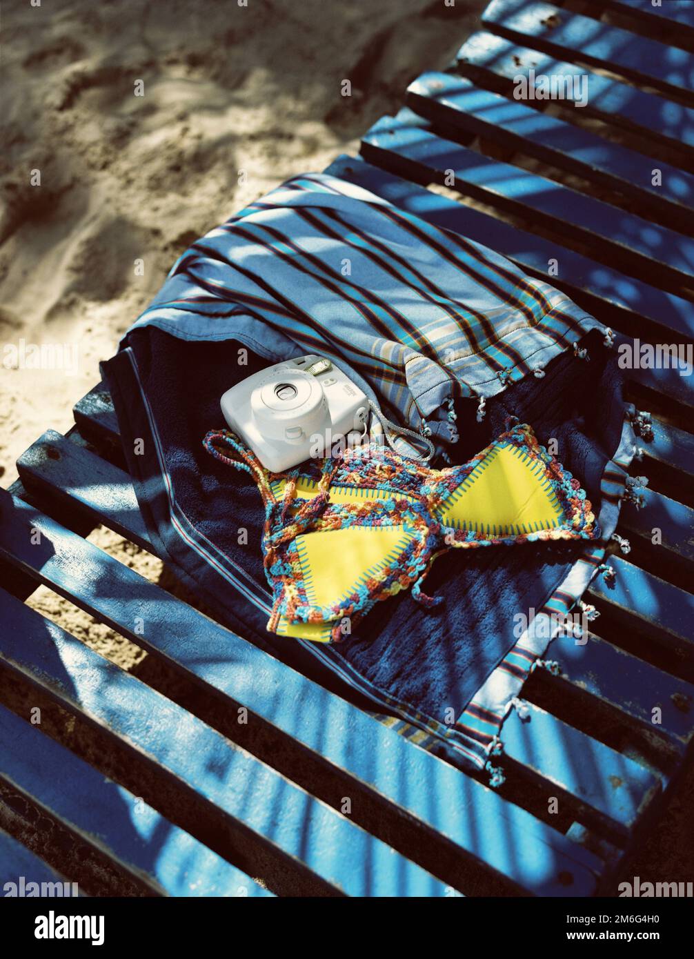 A high-angle shot of a beach scene with a towel, camera and bikini ...