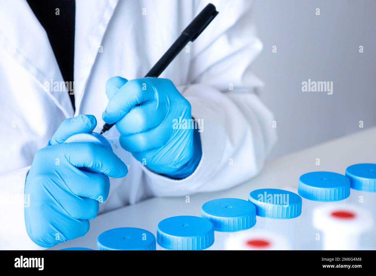 Close-up left handed woman scientist labeling samples with blue gloves ...