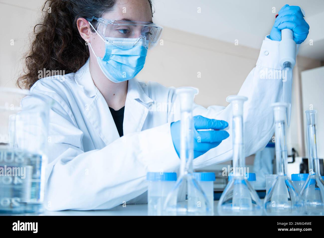 Left handed woman scientist analyzing solutions with blue gloves and equipment. Laboratory ...