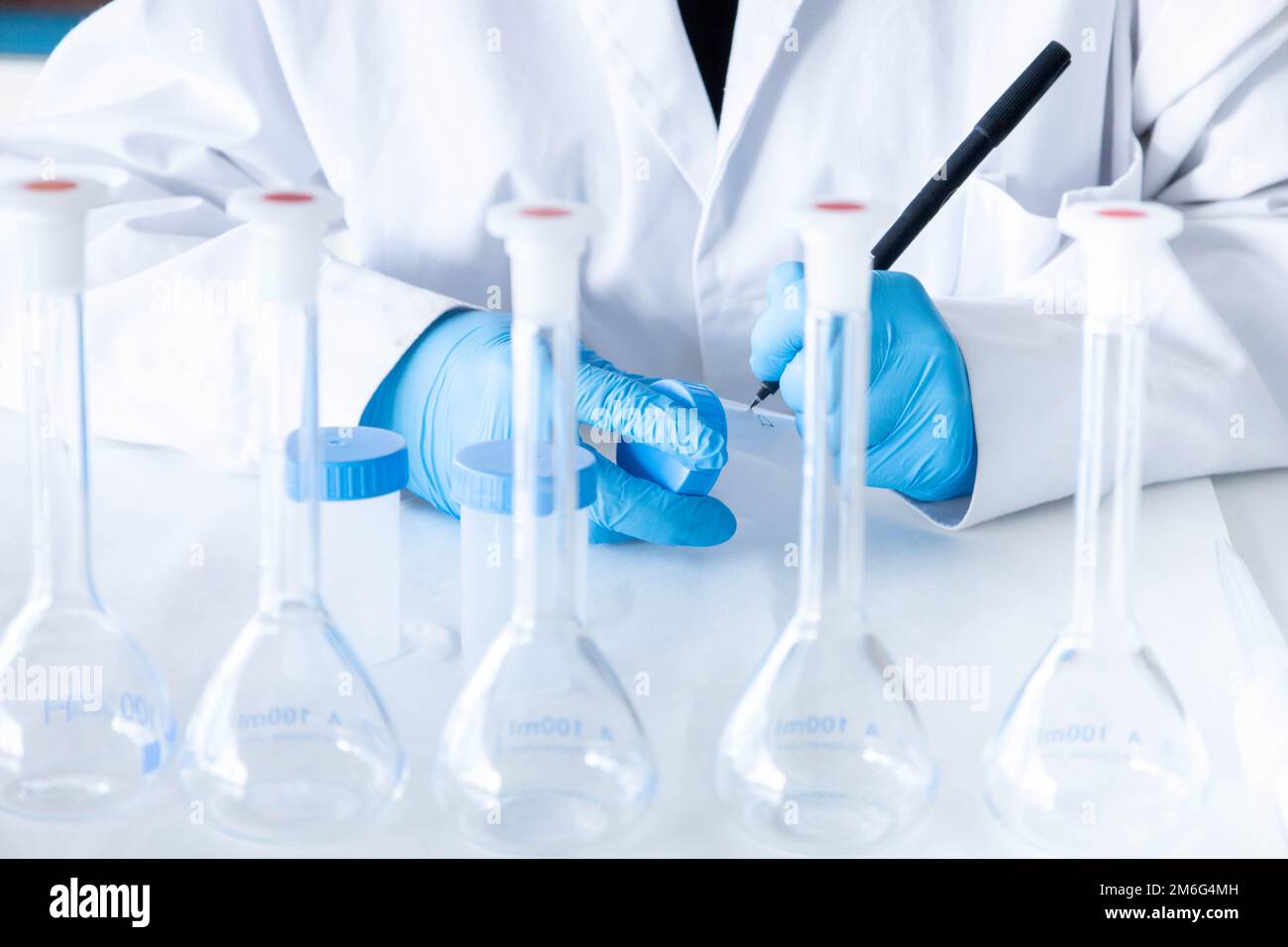 Close-up left handed woman scientist labeling samples with blue gloves ...