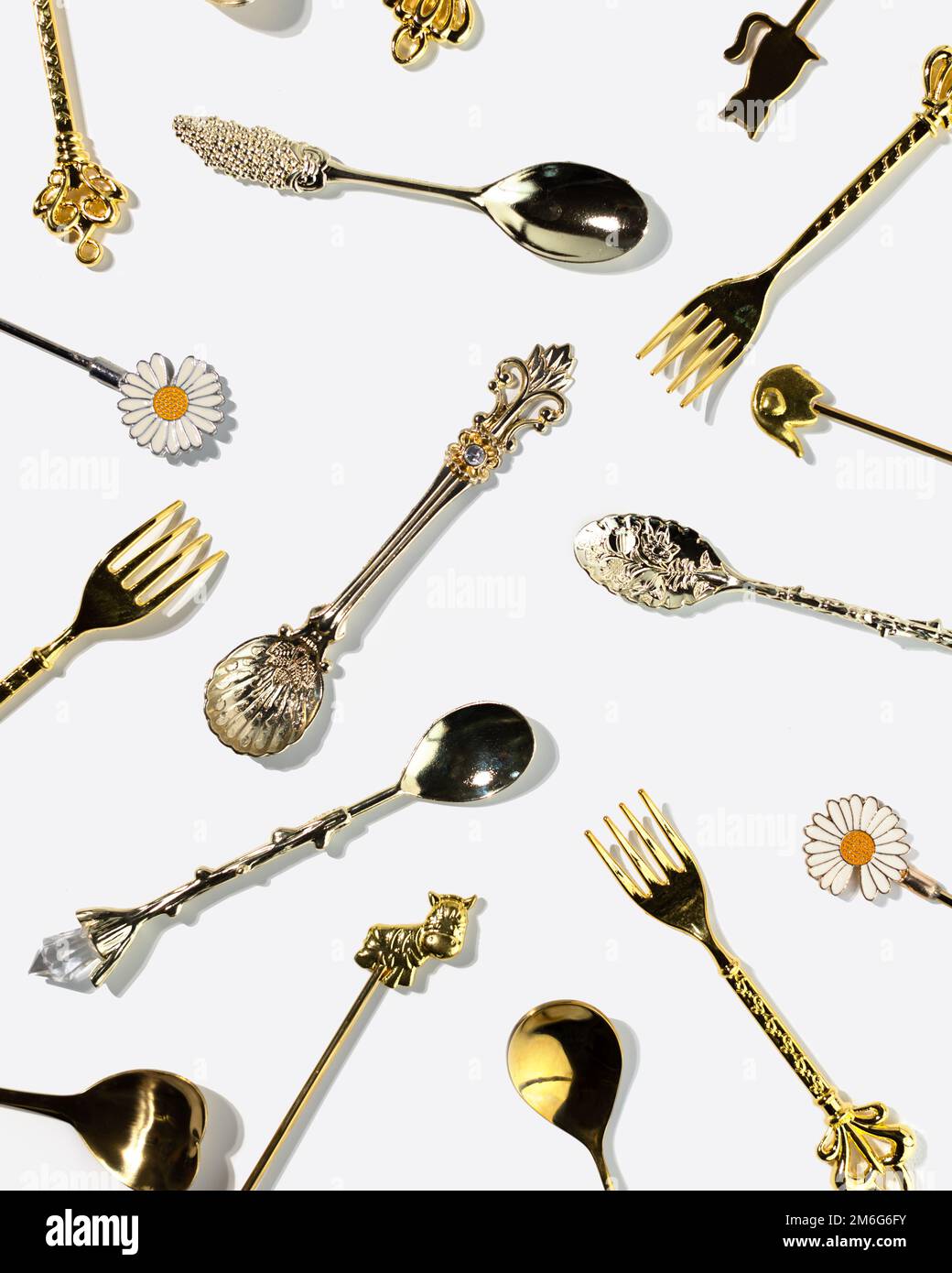 Pattern of golden dessert spoons and forks on white background top view ...