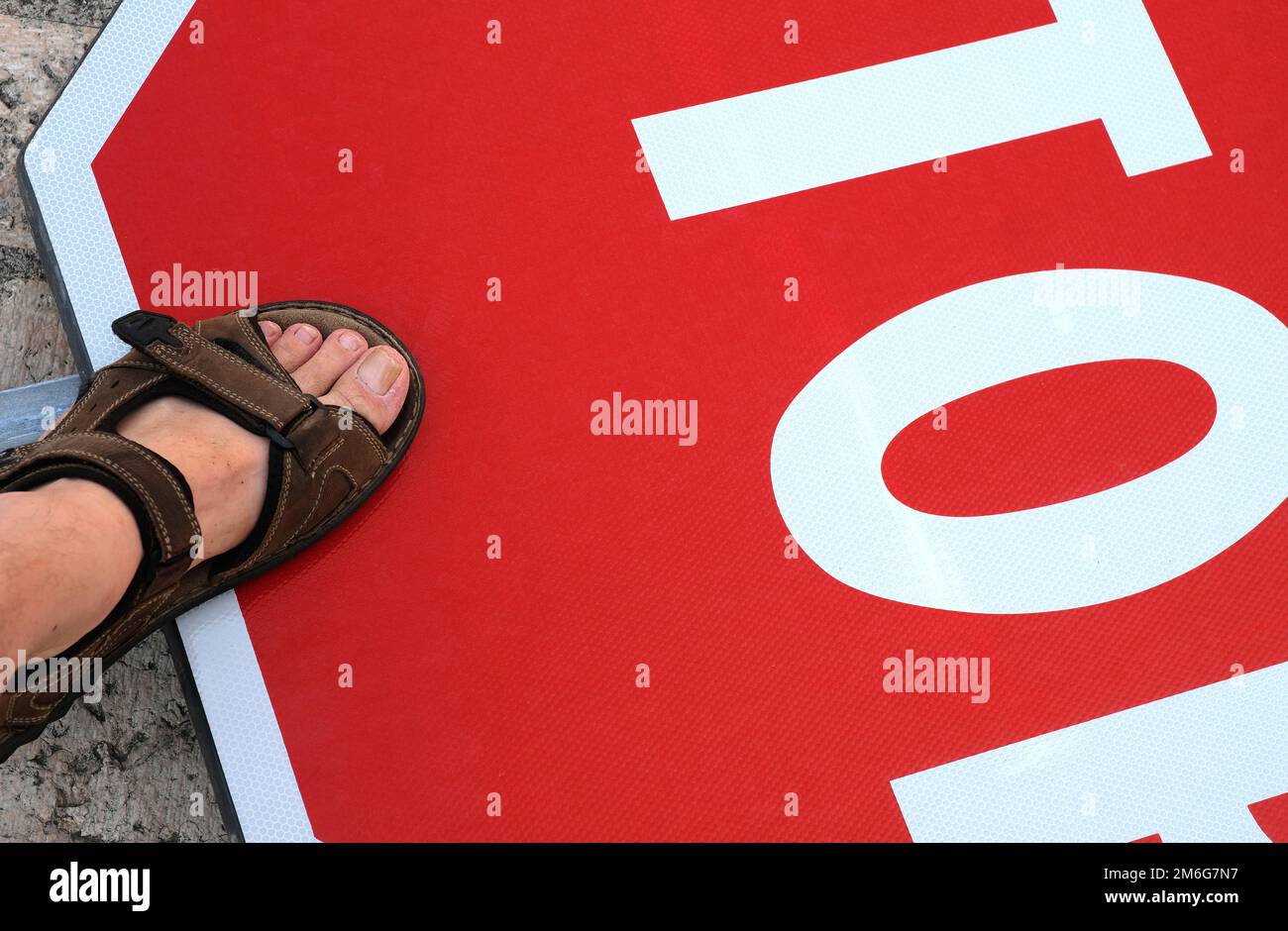 Stop sign on the floor with a foot Stock Photo - Alamy