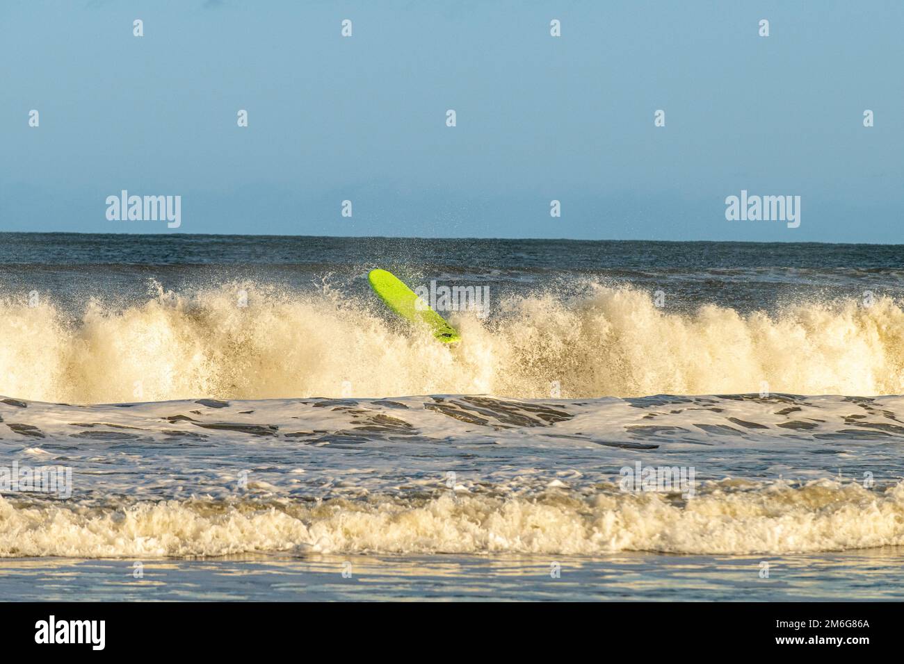 Green surfboard without surfer on the sea at Cayton Bay, North ...