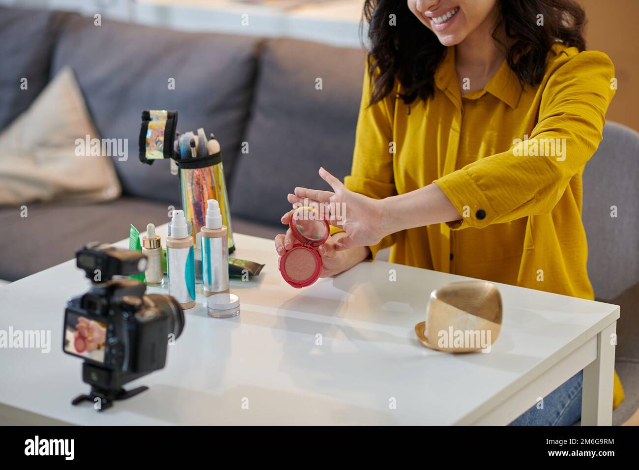 Smiling young woman demonstrating new foundation cream on online ...