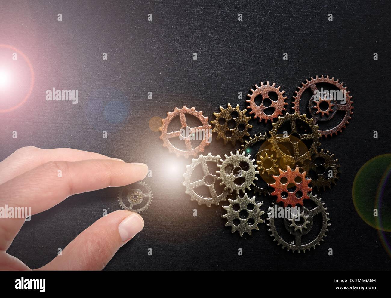 Hand placing a gear into other assorted metal gears to complete a ...