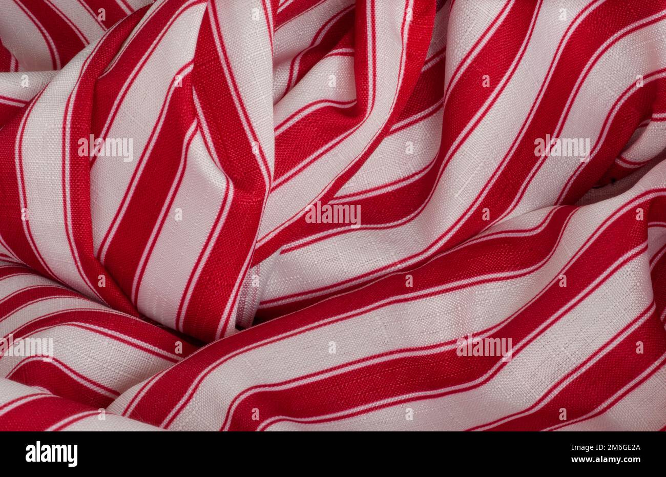 See closeup of red and white stripe fabric in rolls, curves, folds ...