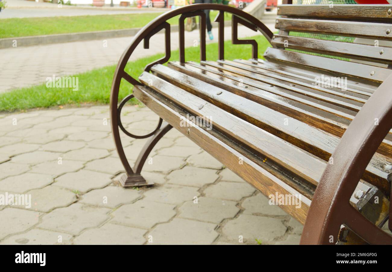 Close-up of a part of a new wooden brown bench with metal handrails ...