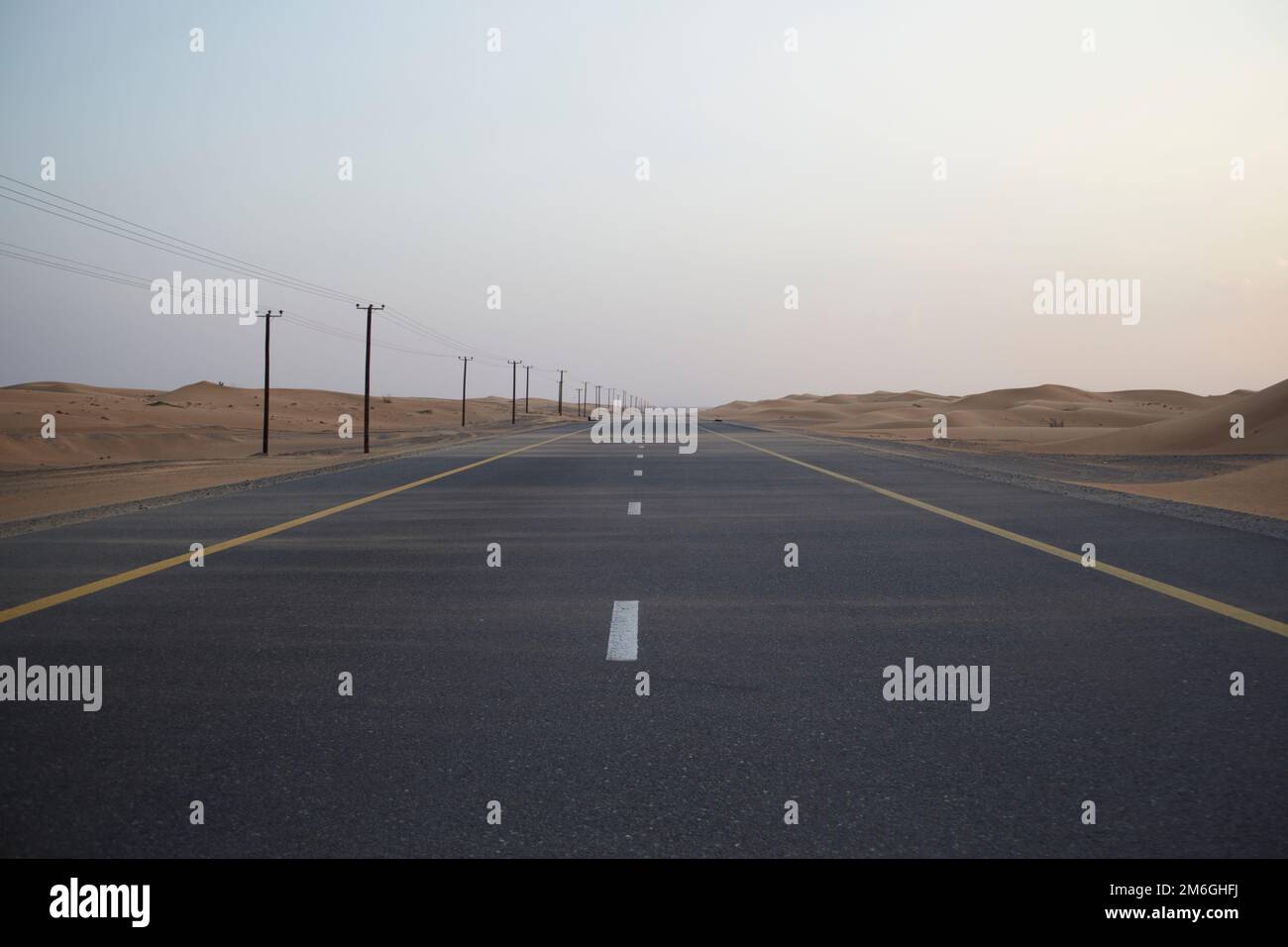 Sand blows across a deserted straight desert highway as it stretches in ...