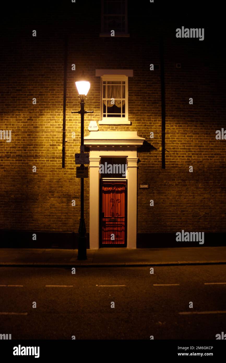 A dark ominous London door way at night lit by a single street light ...