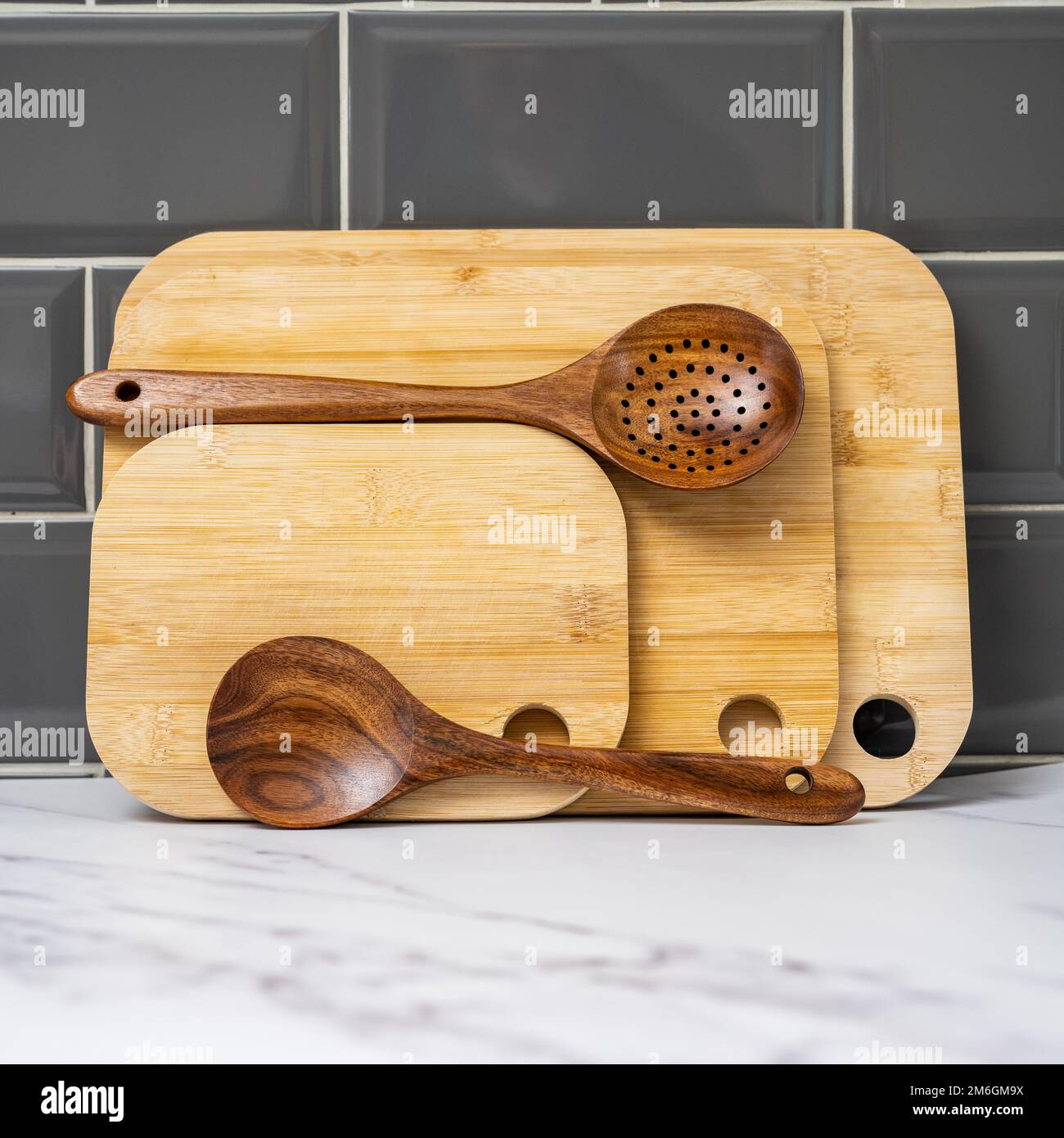 stack of bamboo chopping boards and teak hardwood spoons lined up ...