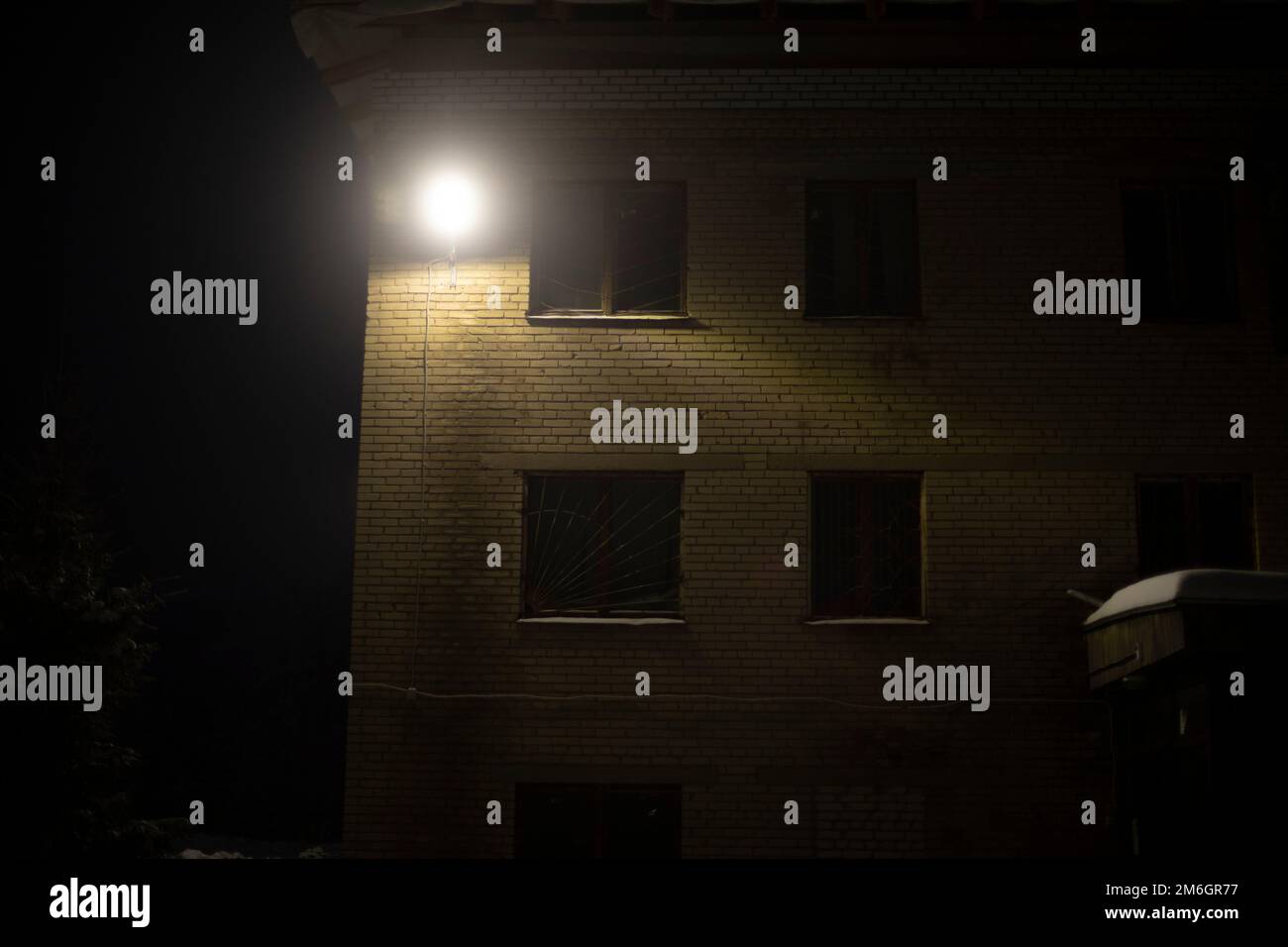 Industrial area at night. Building is in dark. Gates and fence in dark ...
