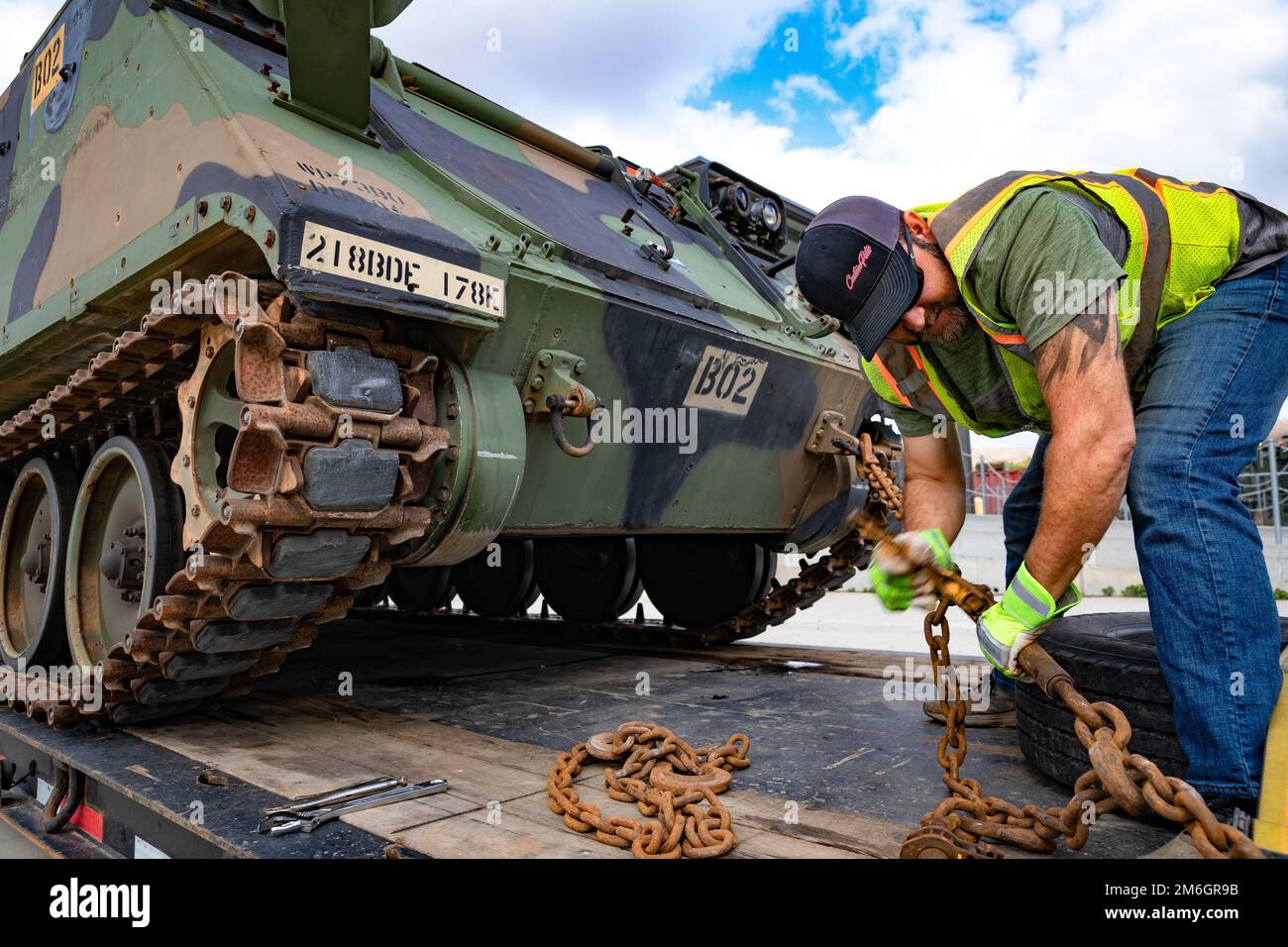 A civilian truck driver secures an M113 Armored Personnel Carrier to a ...