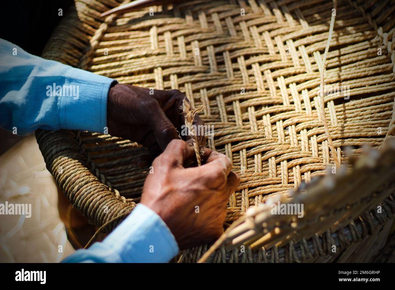 Skilled craftsman working manually a detailed bamboo wood armchair with ...