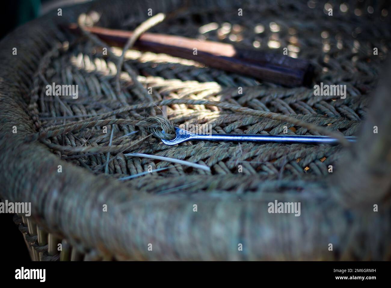 Skilled craftsman working manually a detailed bamboo wood armchair with ...