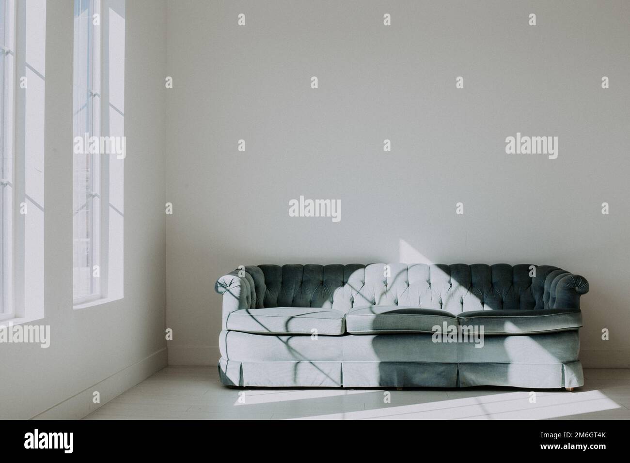 Blue midevil couch sitting in minimal white, natural light room Stock ...