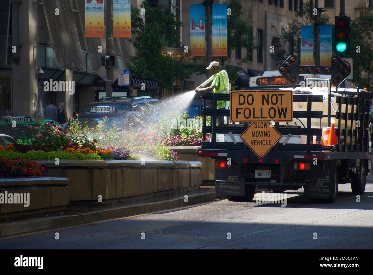 A street worker waters the flowers in the central reservation of ...