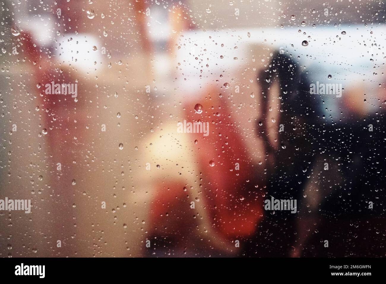 Rain is seen on a train window with a station out of focus behind Stock ...