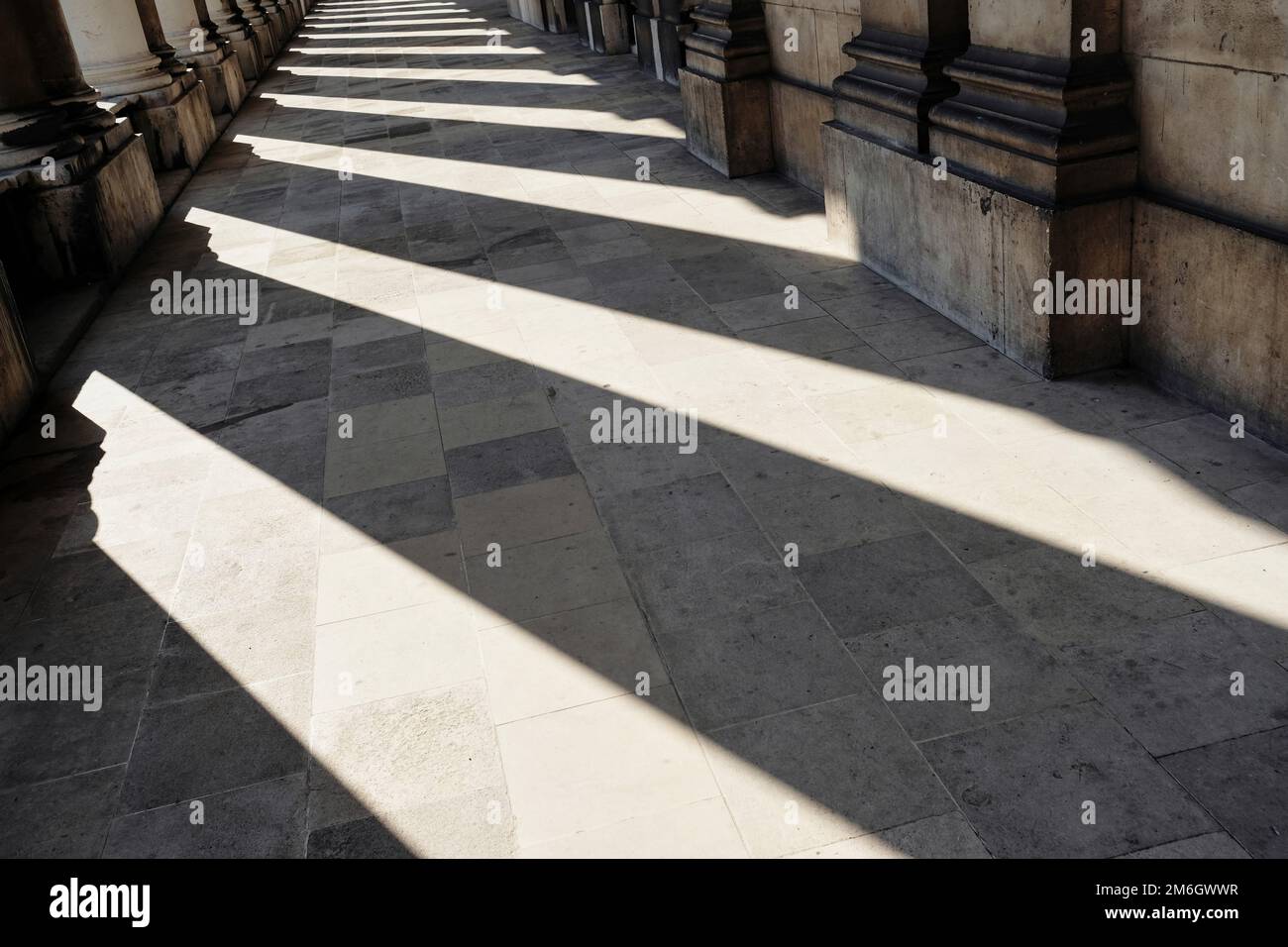 shafts of sunlight through columns create stripes of shadow and light ...