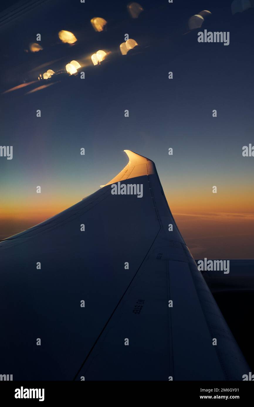 An aeroplane wing in flight with a reflection of the sun seen through ...