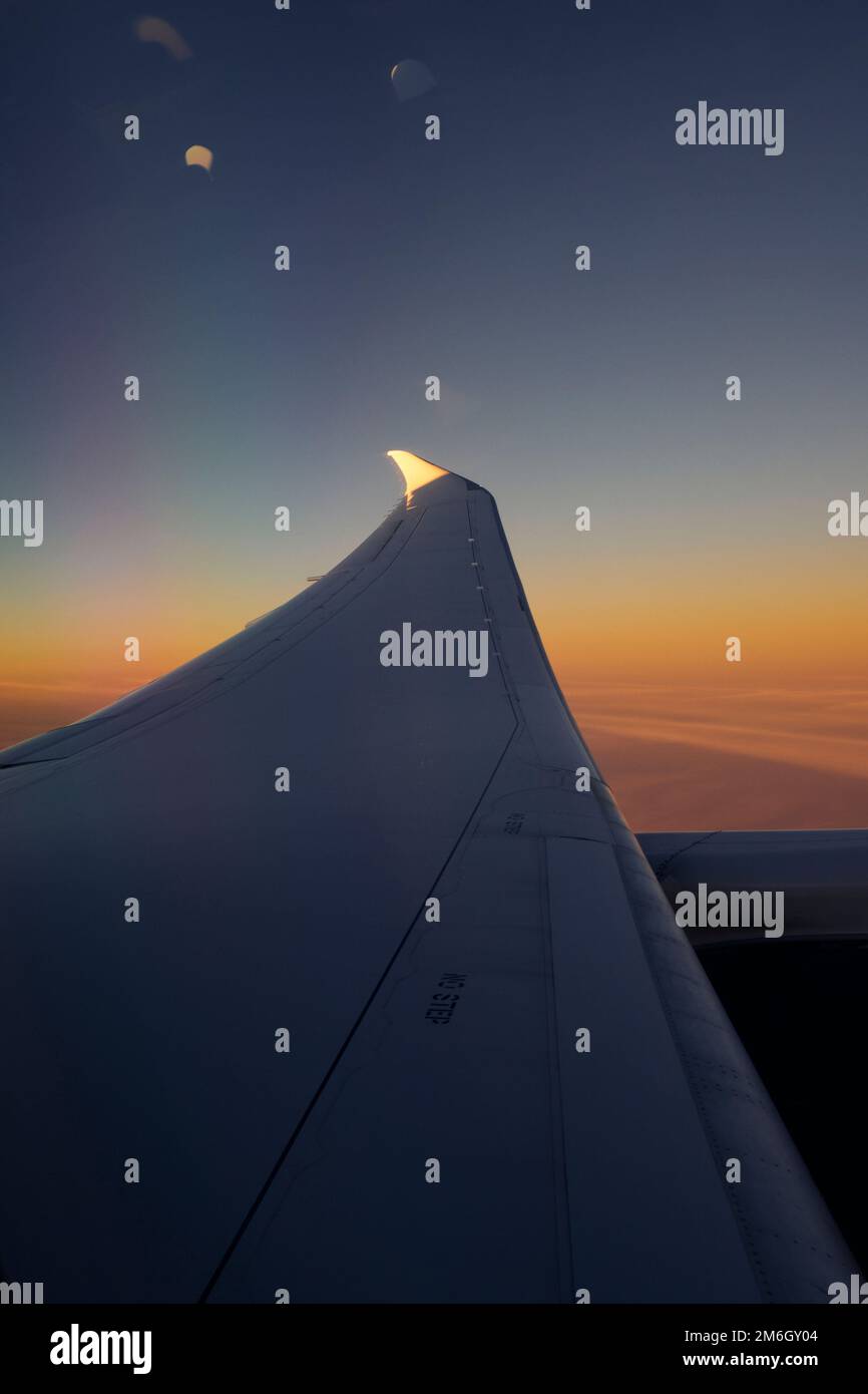 An aeroplane wing in flight with a reflection of the sun seen through ...
