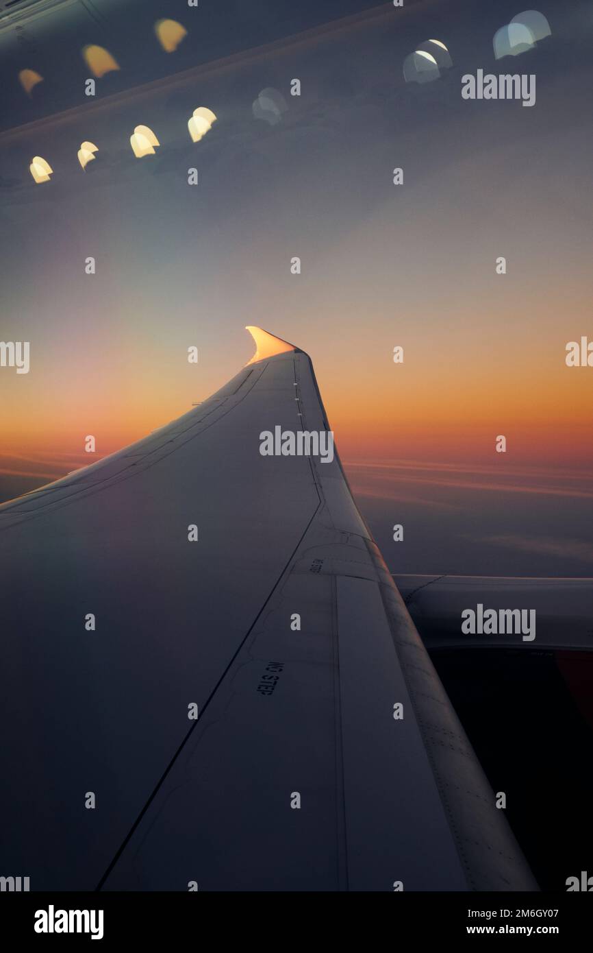 An aeroplane wing in flight with a reflection of the sun seen through ...