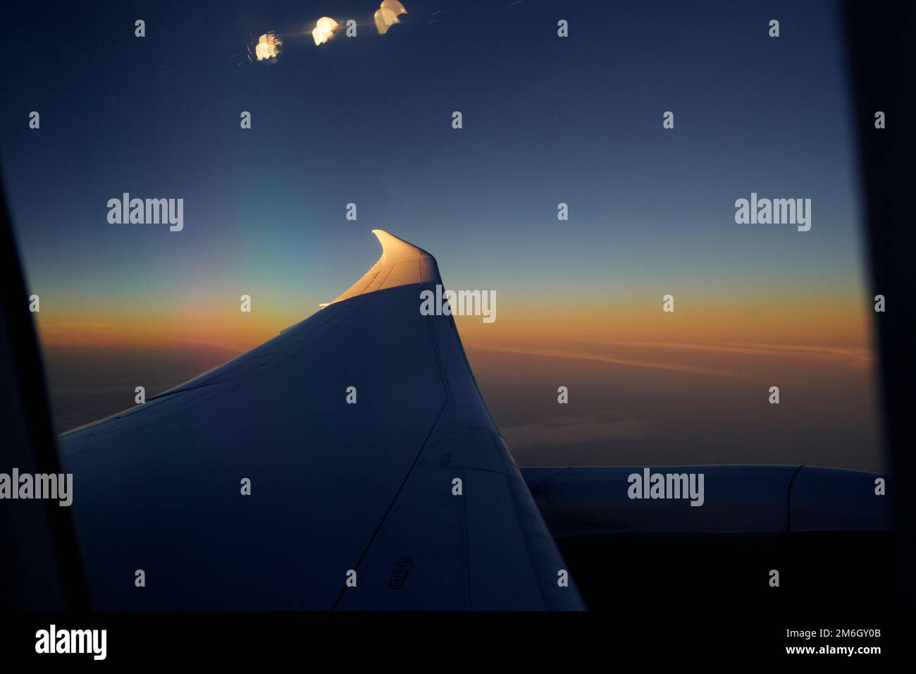 An aeroplane wing in flight with a reflection of the sun seen through ...