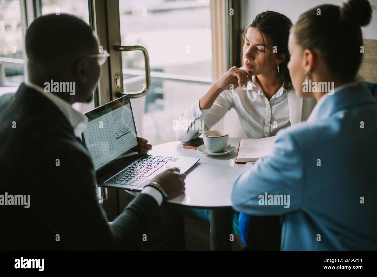 Three bussinesspeople looking at statistics and charts for their recent ...