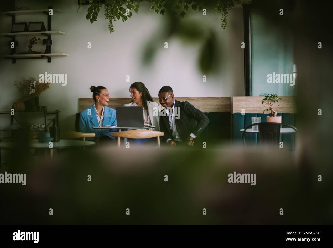 Three busines colleagues laughing together while sitting at the blue sofa at the cafe Stock ...