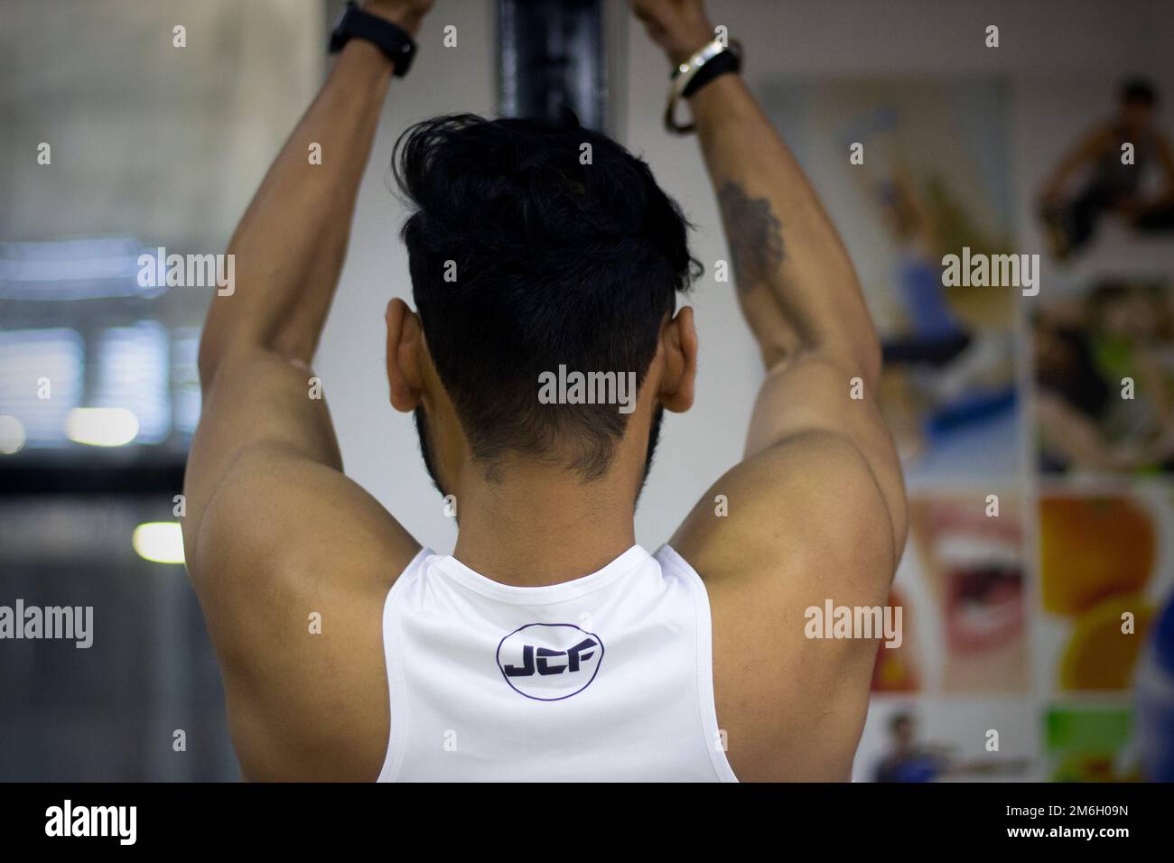 Strong muscle man closeup doing exercise in gym weightlifting equipment ...