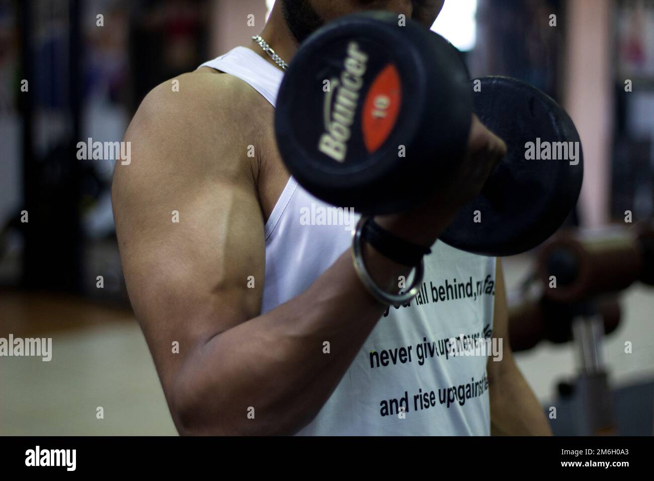 Strong muscle man closeup doing exercise in gym weightlifting equipment ...
