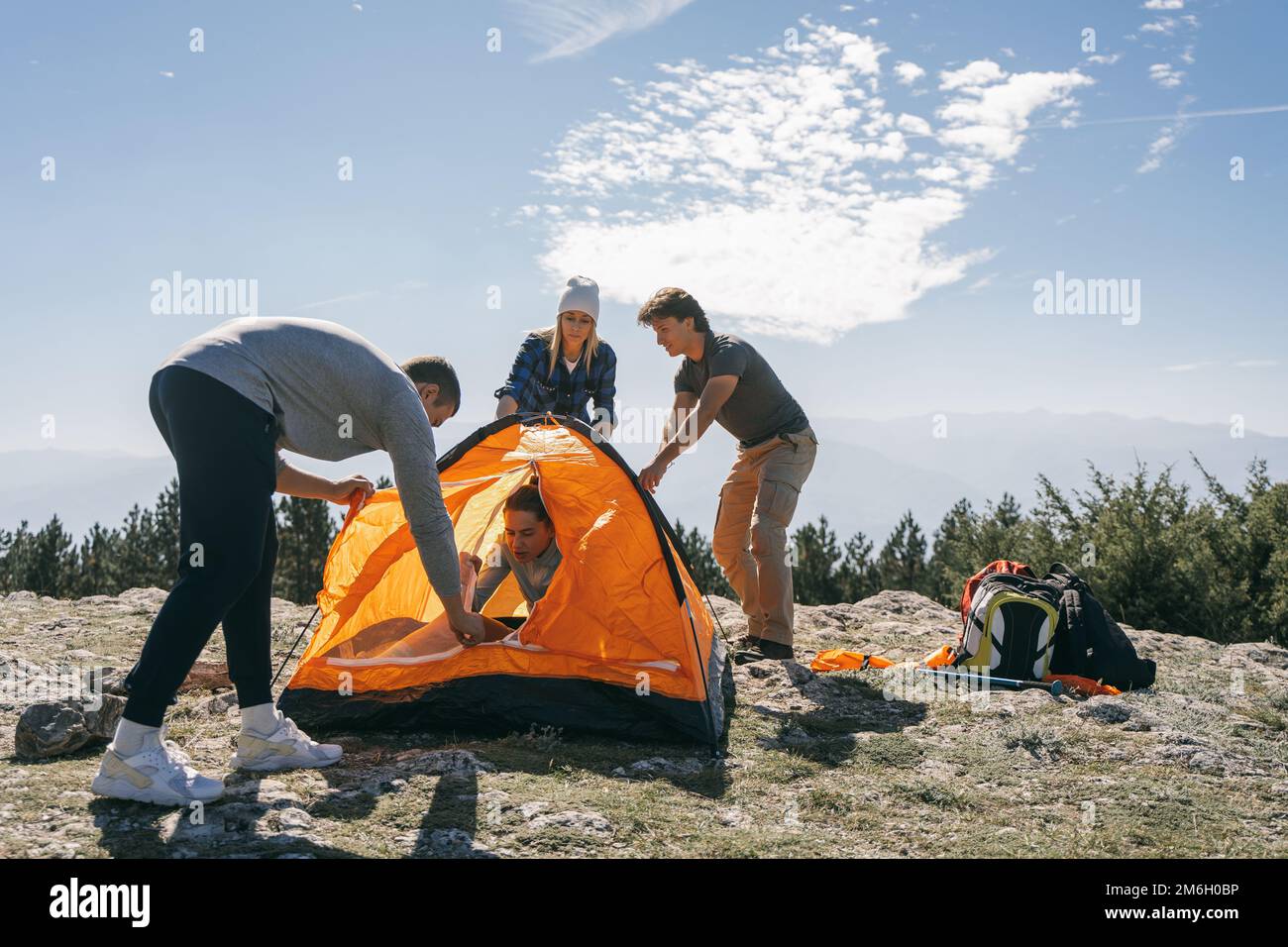 Group of friends moving the orange tent with their friend inside Stock ...