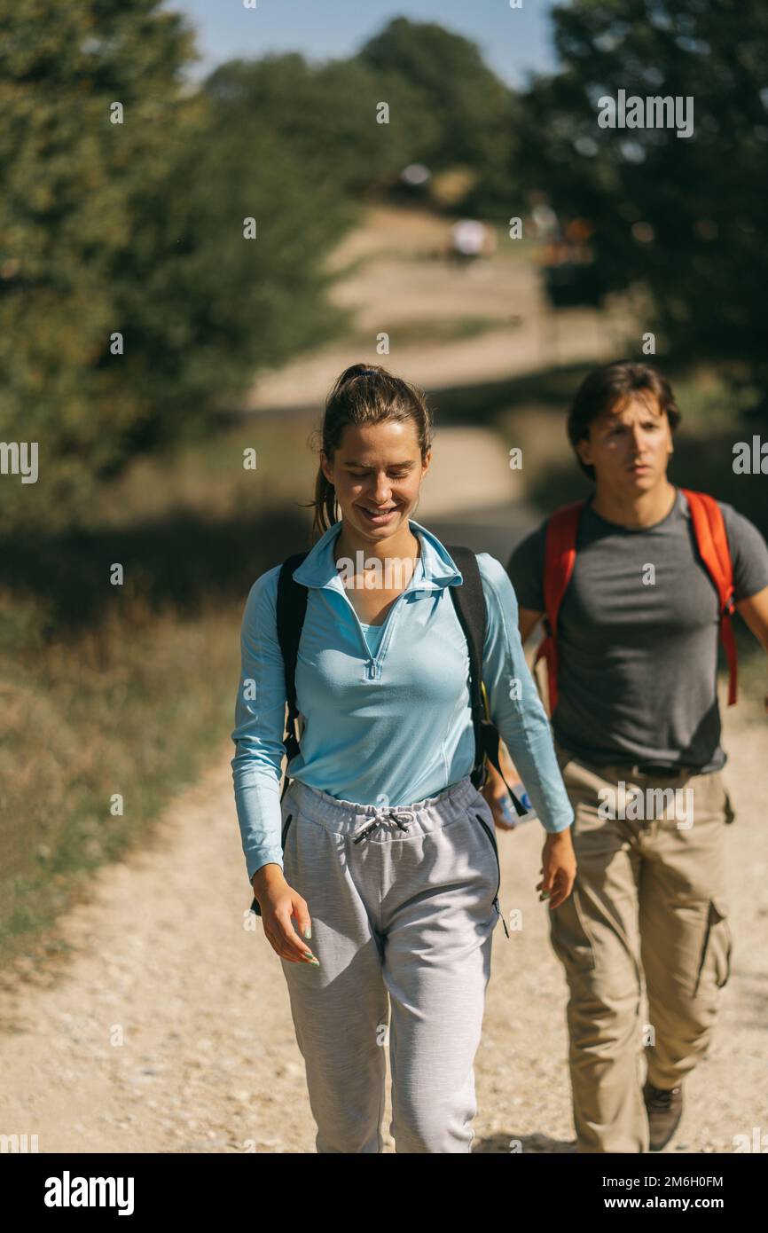Smiley gorgeous female hiker walking and smiling while her friend is ...