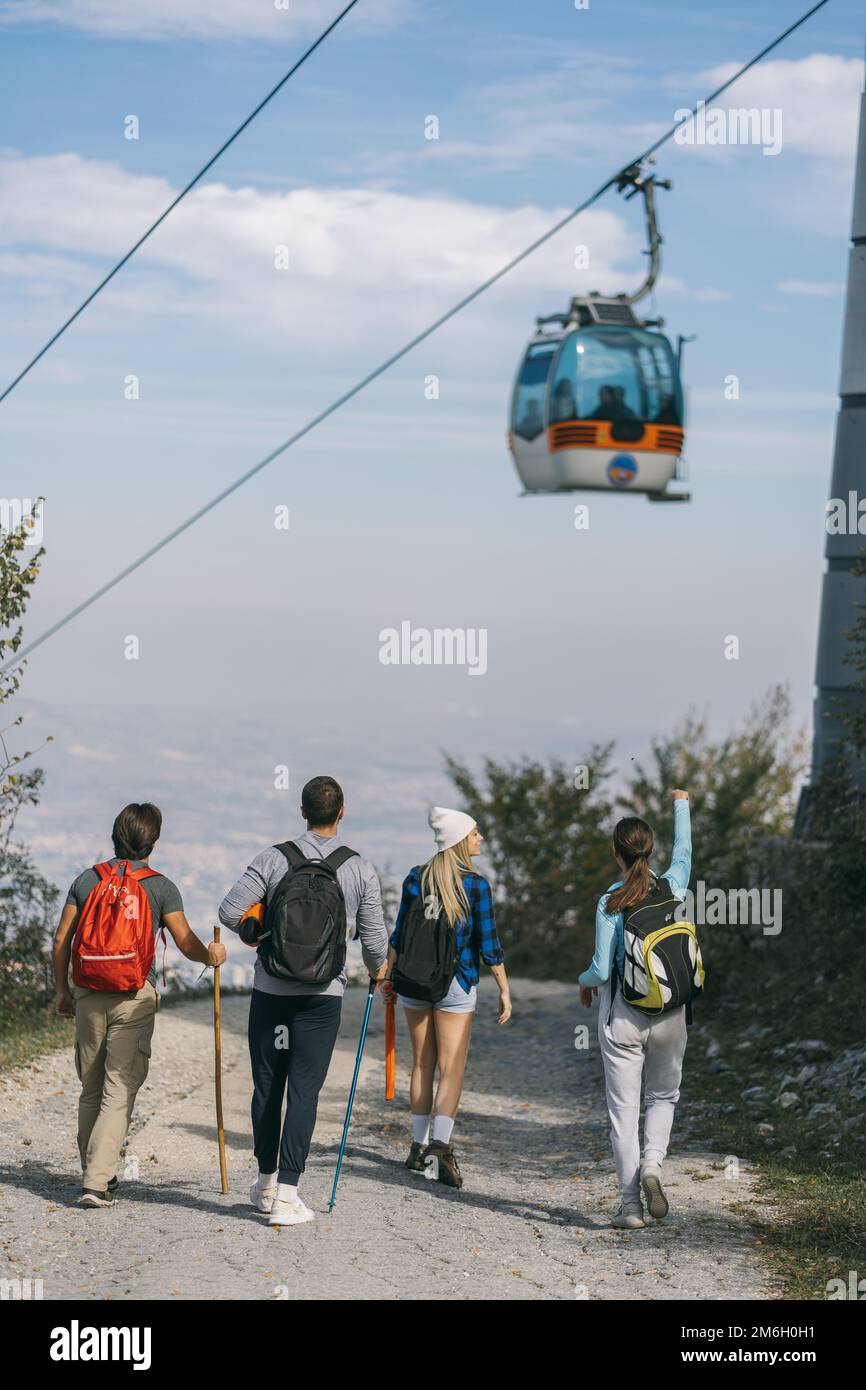 Two sports couples reaching the top of the mountain. Zip line passing ...