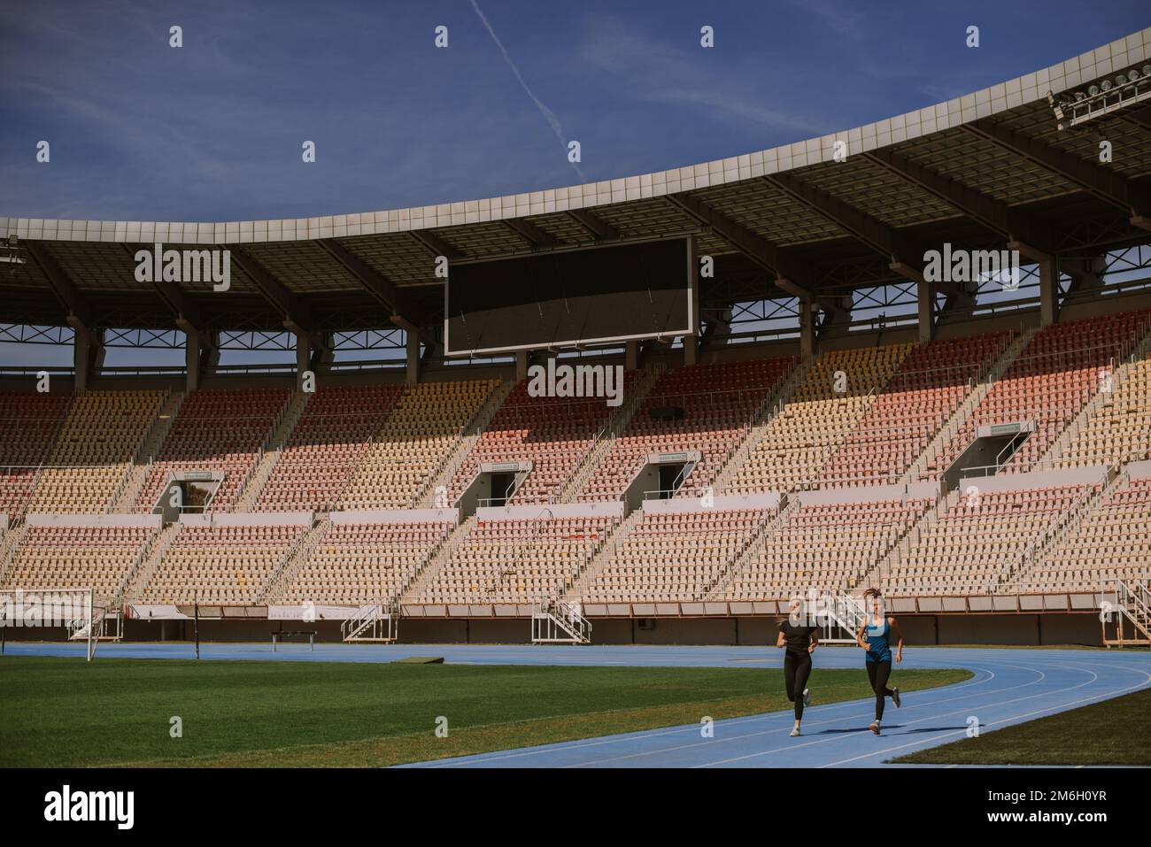 Cardio exercising. Two girls running around the stadium Stock Photo - Alamy