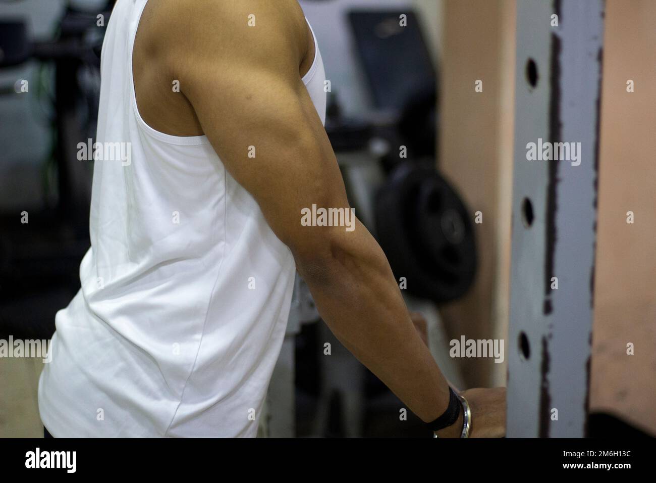 Strong muscle man closeup doing exercise in gym weightlifting equipment ...