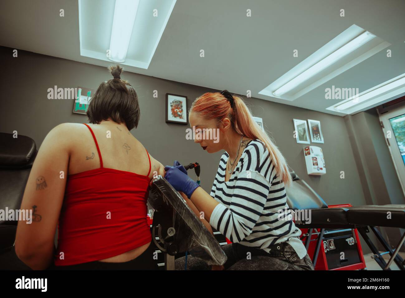 Tattoo artist tattooing her client while sitting at the studio Stock ...