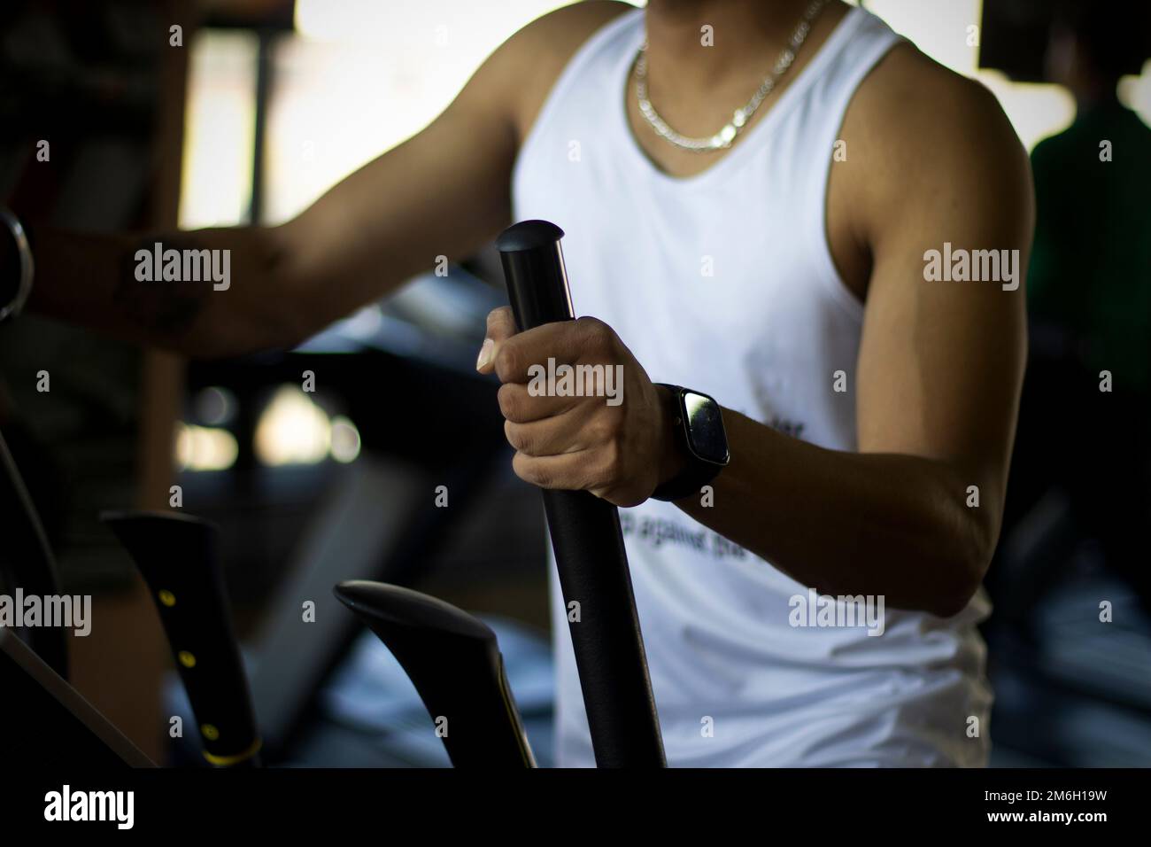Strong muscle man closeup doing exercise in gym weightlifting equipment ...
