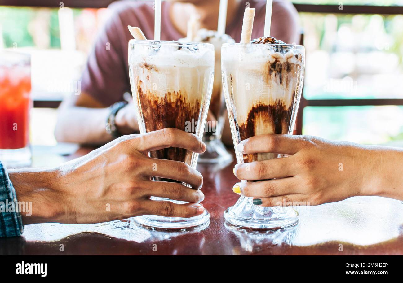 Man and woman hand toasting and holding two milkshake. Two hands ...