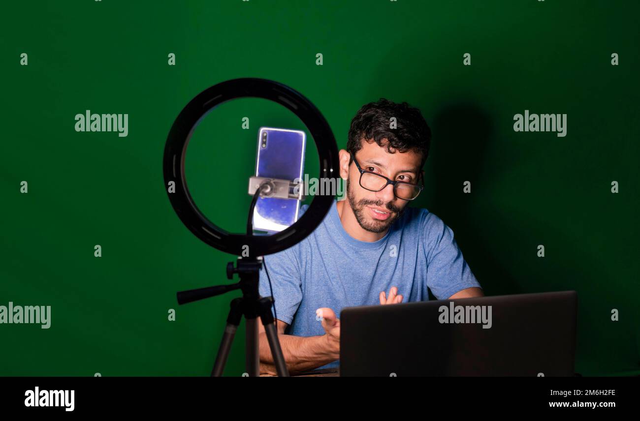 Guy with laptop making video blog on phone. Isolated person giving ...