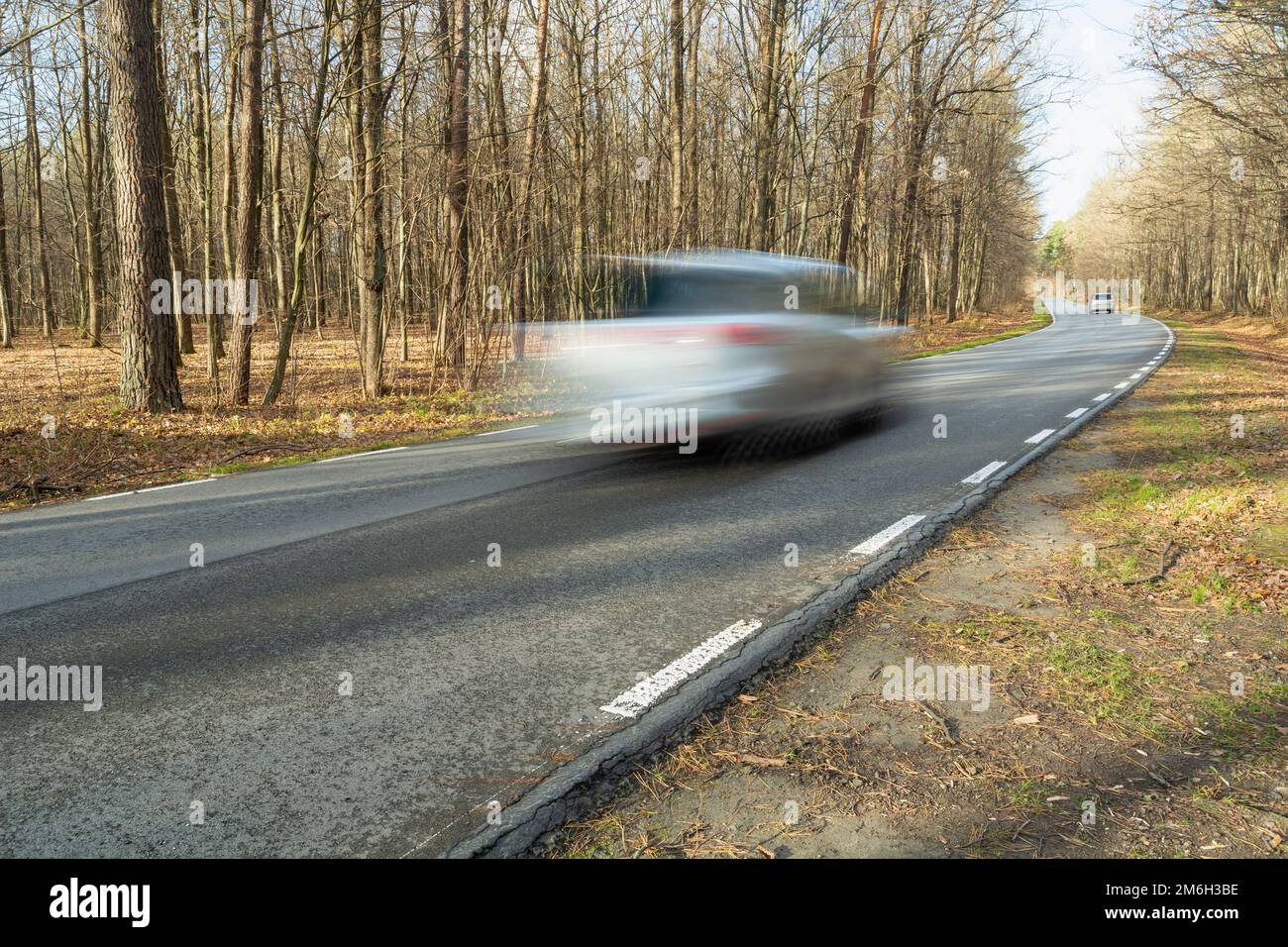 A car driving fast on an asphalt road through the forest Stock Photo ...