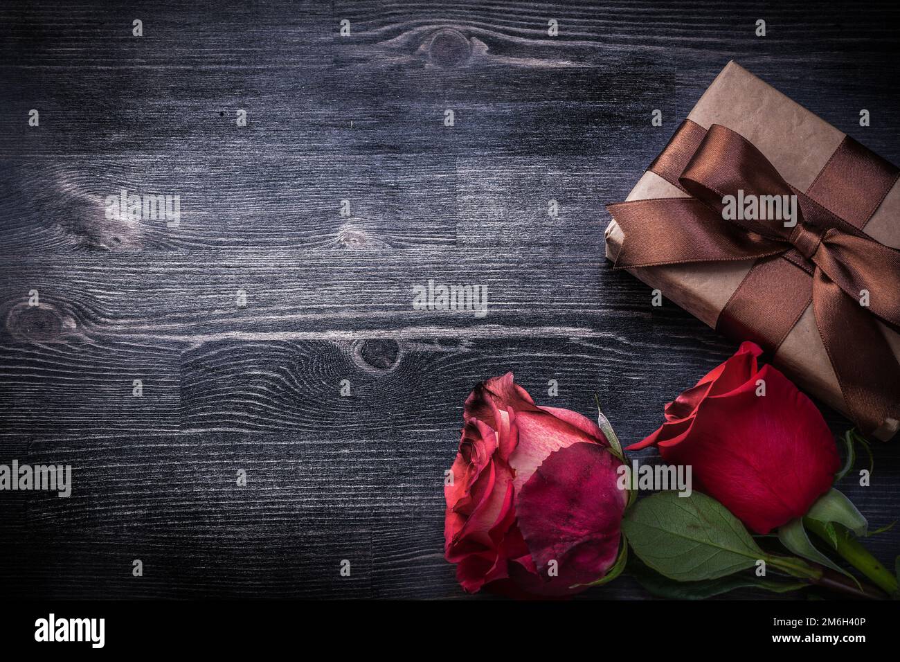 Bloomed rosebuds wrapped present box on wooden background holidays ...