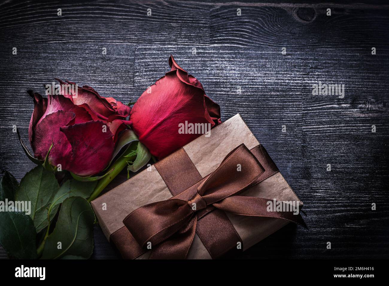 Bloomed rosebuds packed present box on wooden background holidays ...