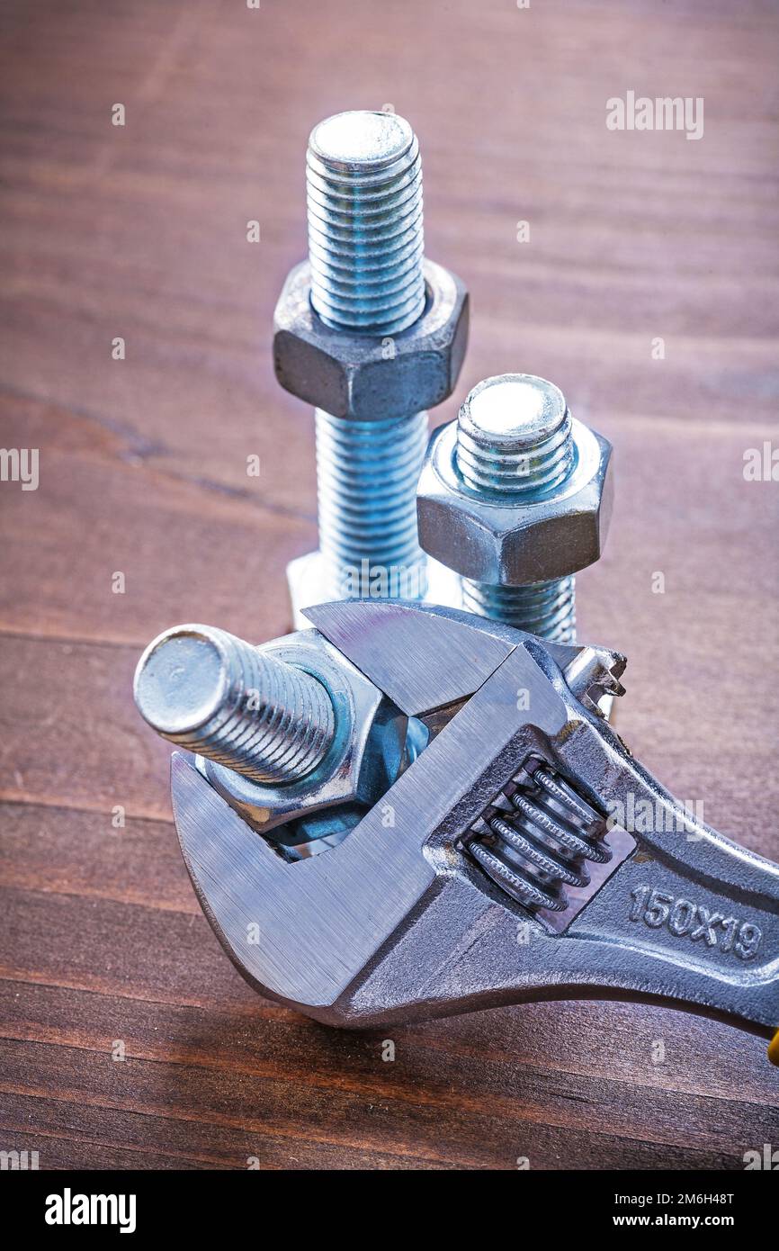 Brown wooden board with adjustable spanner metal threaded bolts and ...