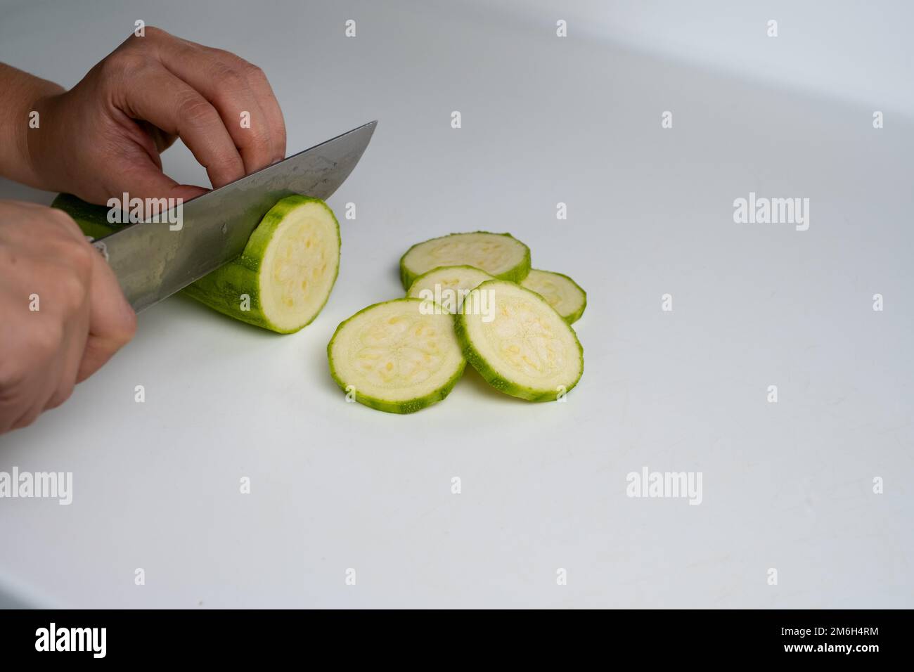 Female hand cutting zucchini. Hand is cutting green zucchini with a ...