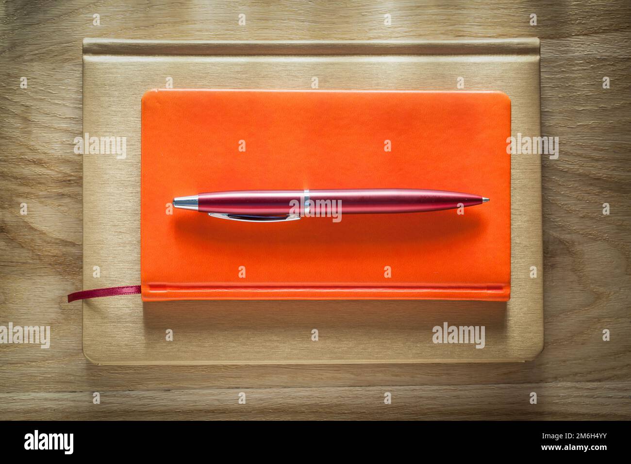 Closed notepads biro pen on wooden board Stock Photo - Alamy